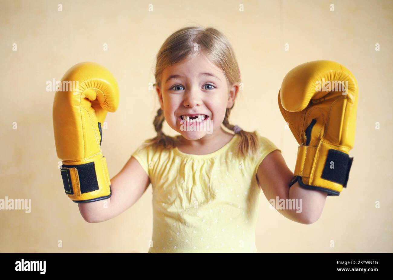 Little girl with yellow boxing gloves over yellow wall background. Girl ...