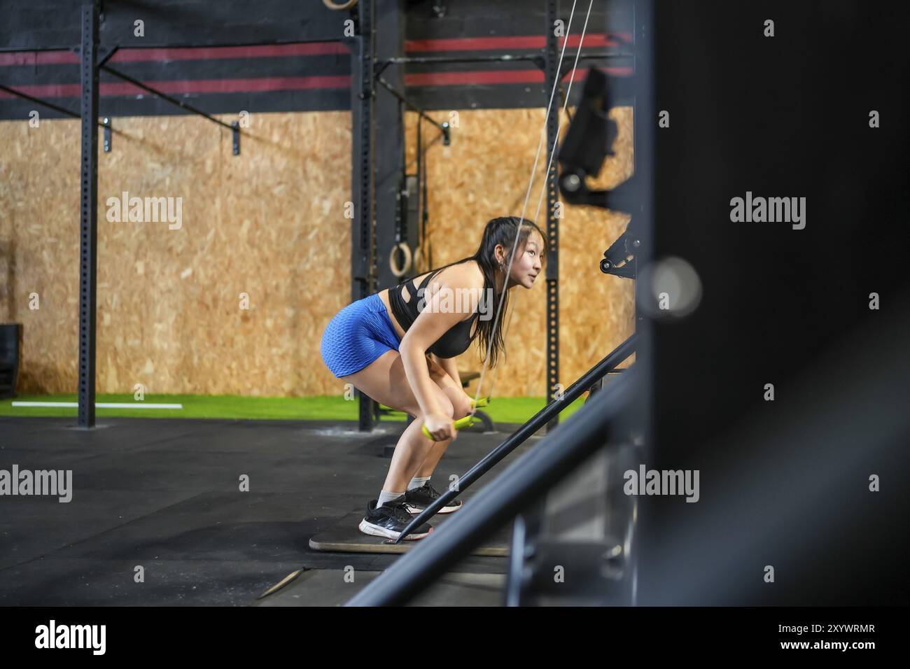Full length side view of a Chinese woman pulling weights with lat ...