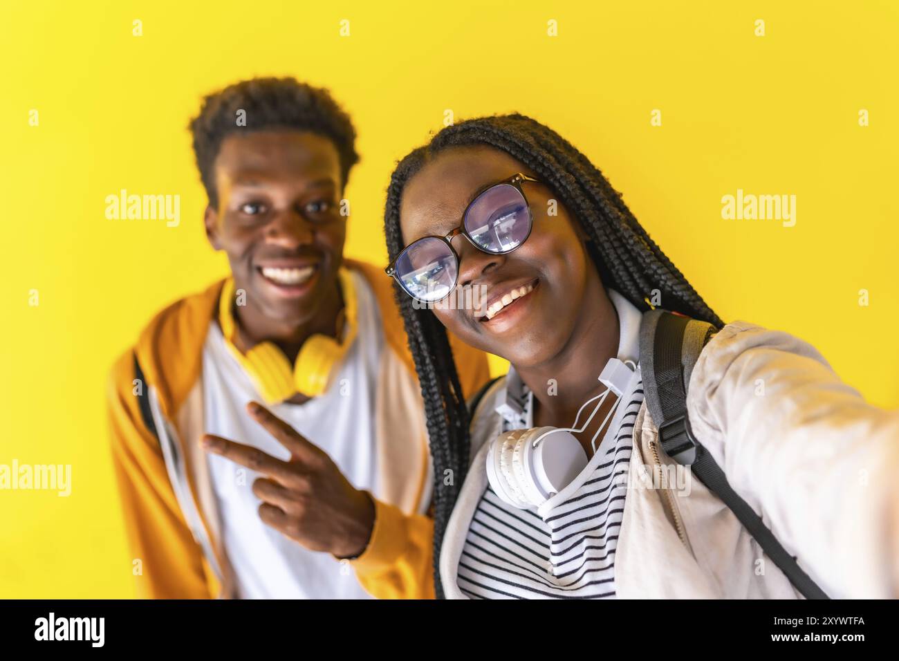 Studio portrait with yellow background of two male and female african university students taking ...
