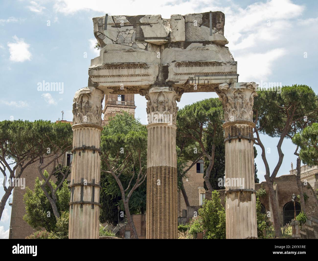 Three old columns in front of a cloudy sky and green background with ...