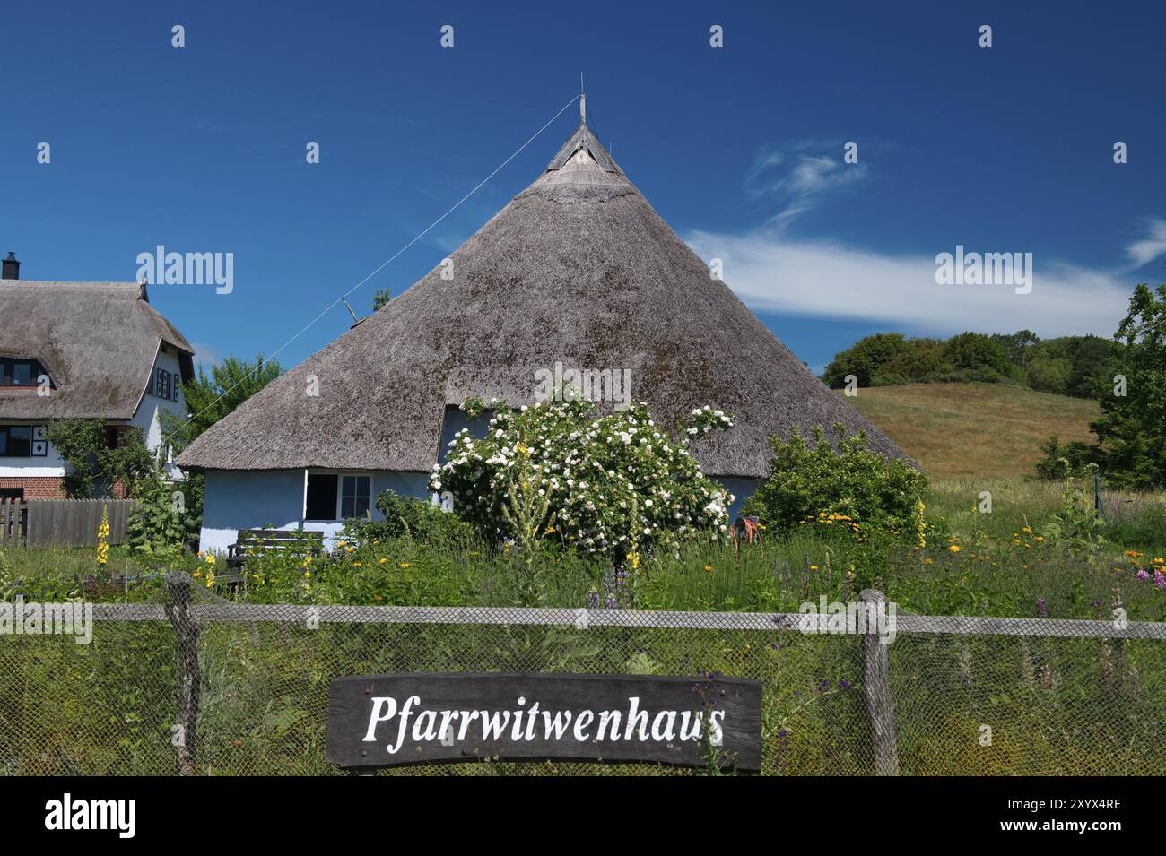 Historic parish widow's house with thatched roof and sign in the front ...
