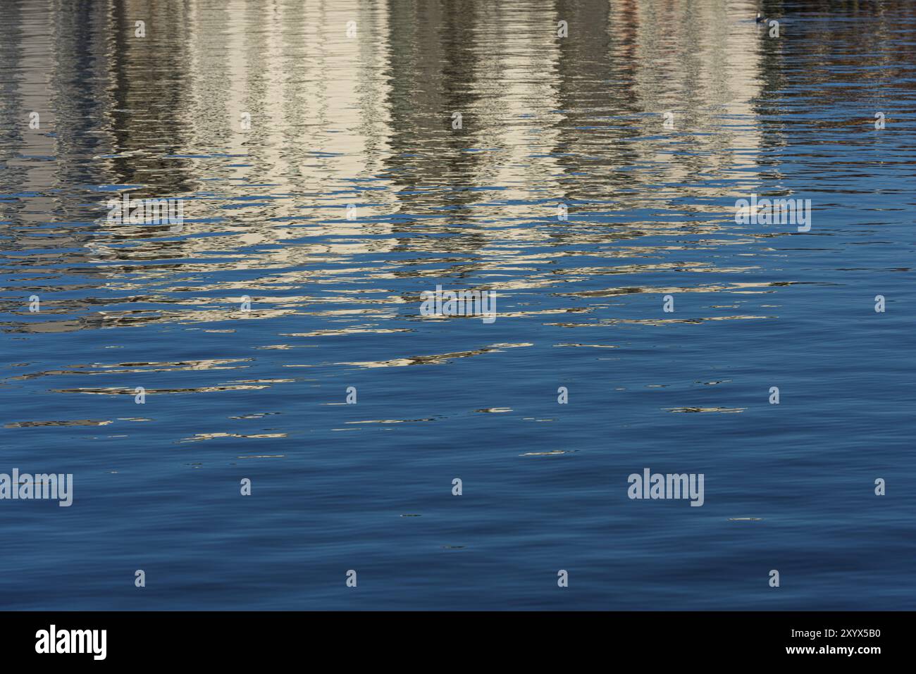 Water with small waves. Reflections of blue sky and buildings Stock ...