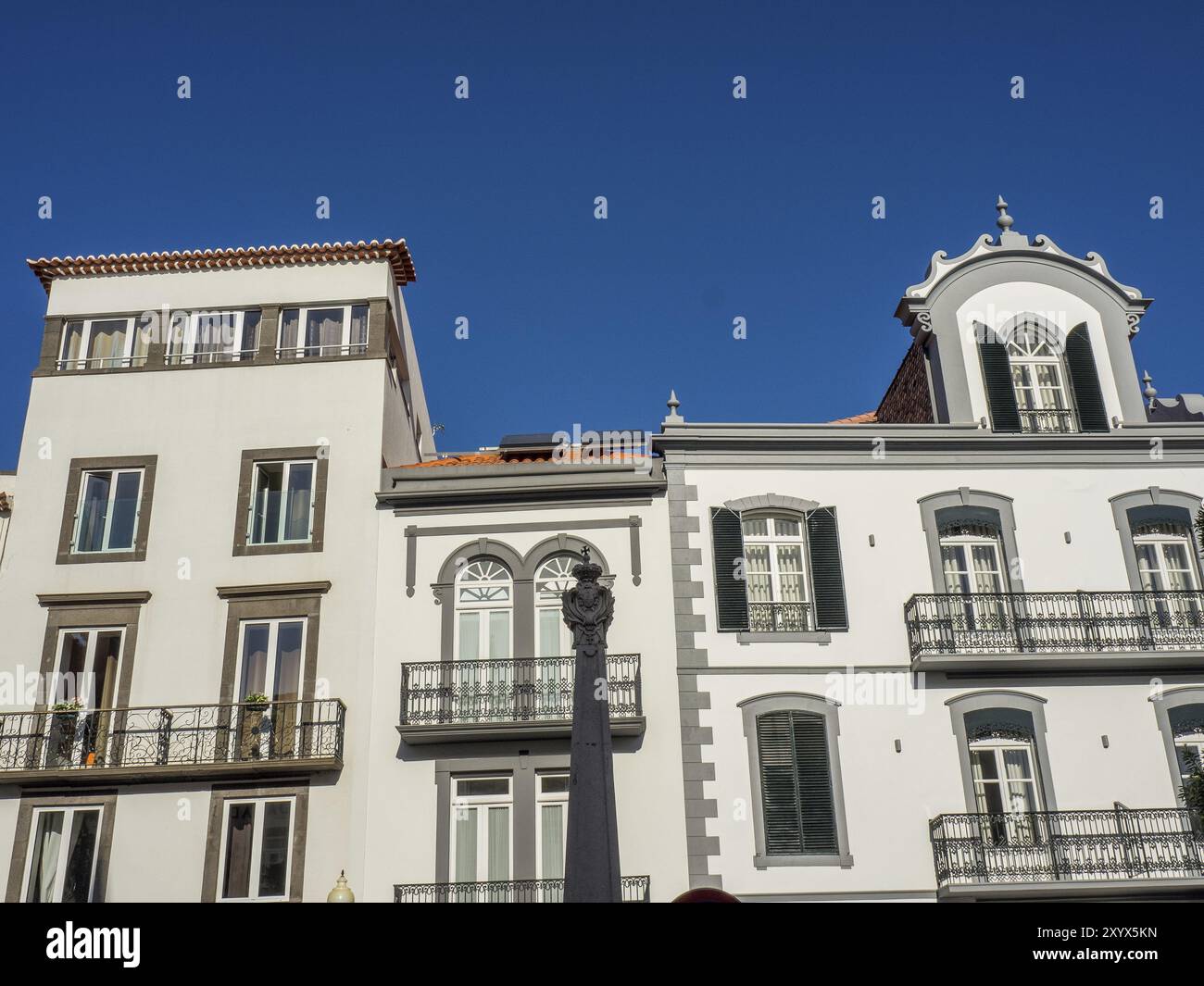 White buildings with balconies and classic details under a clear blue ...