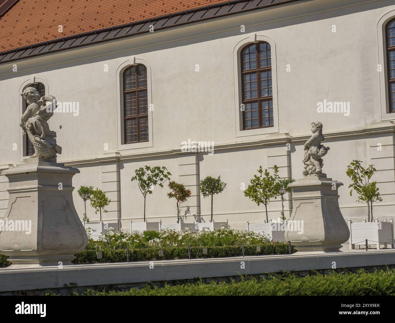 Two baroque statues in a well-kept garden in front of a historic ...