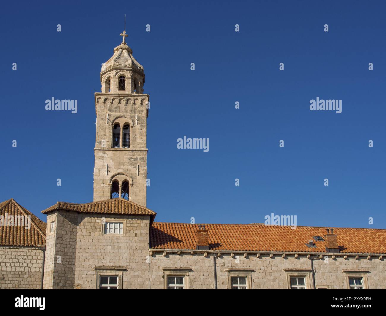 A tall church tower with a tiled roof under a clear blue sky, showing ...