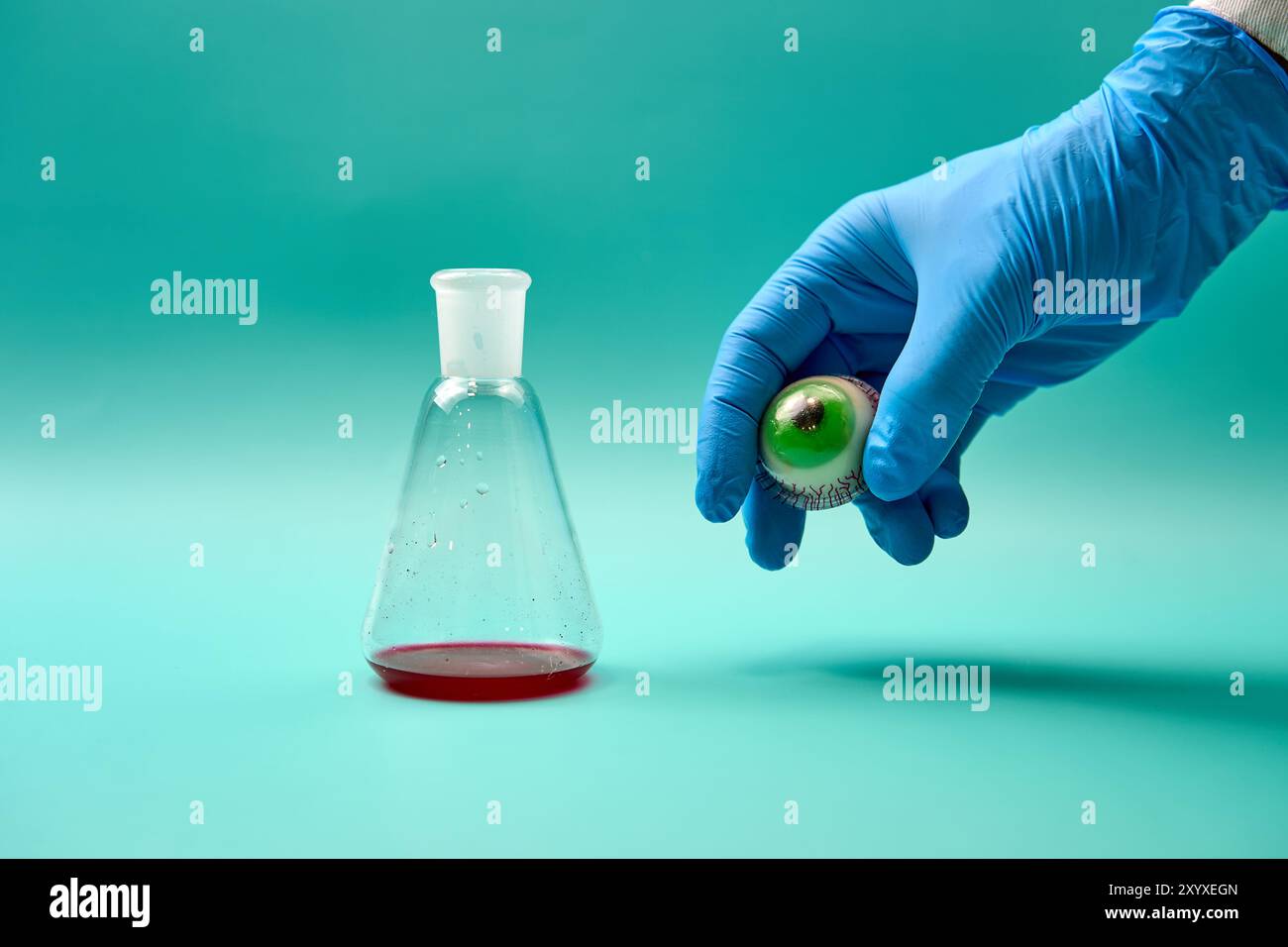 Conical flask with red substance and hand holding artificial eyeball ...