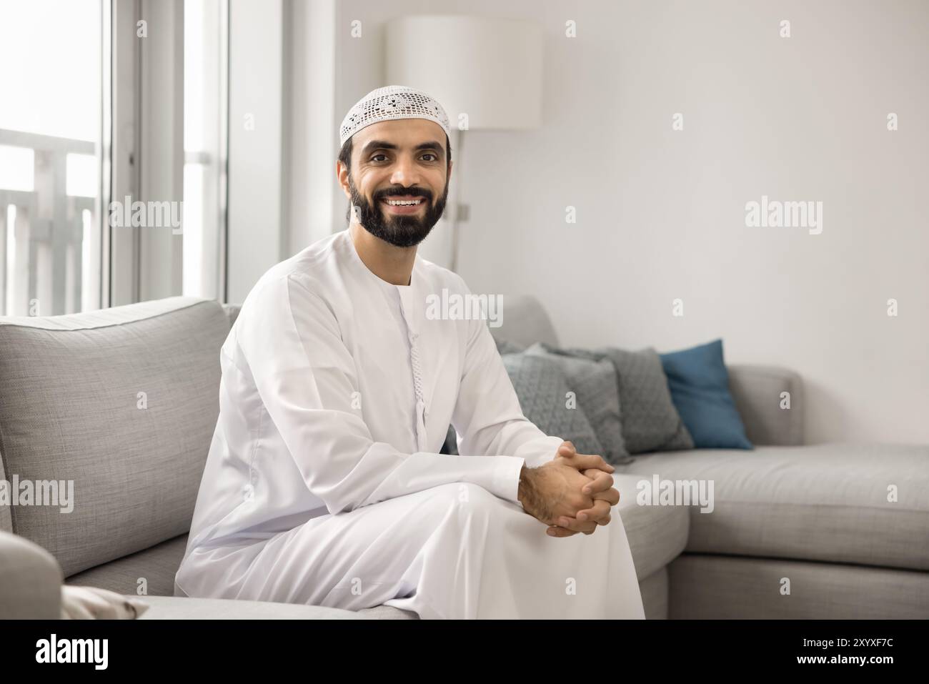 Happy handsome Middle Eastern man sitting on home couch Stock Photo - Alamy