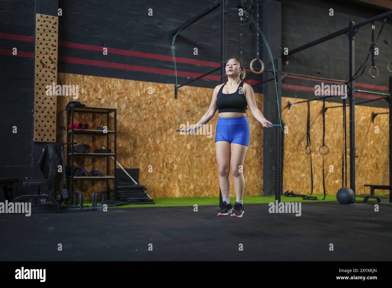 Full length photo of a Chinese woman warming up jumping rope alone in ...