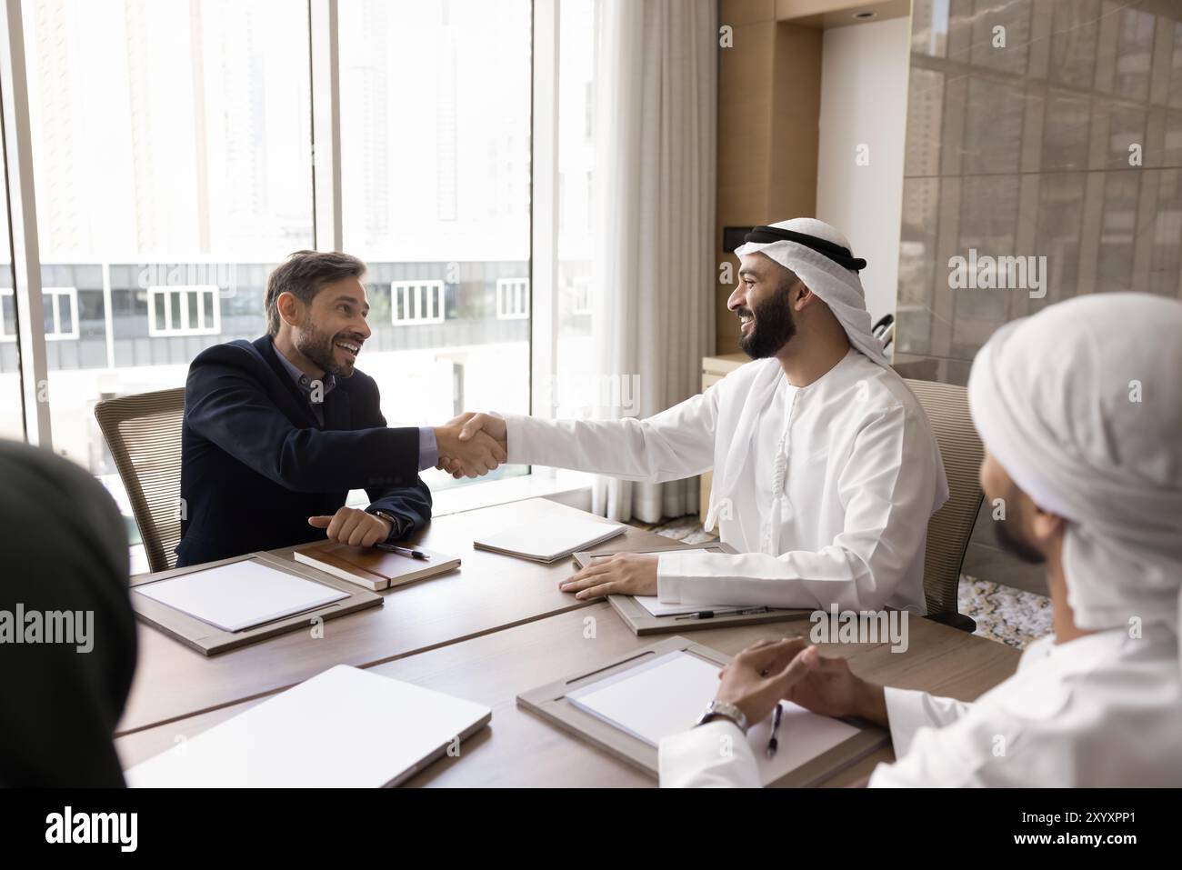 Happy multiethnic business partners finishing successful negotiation ...