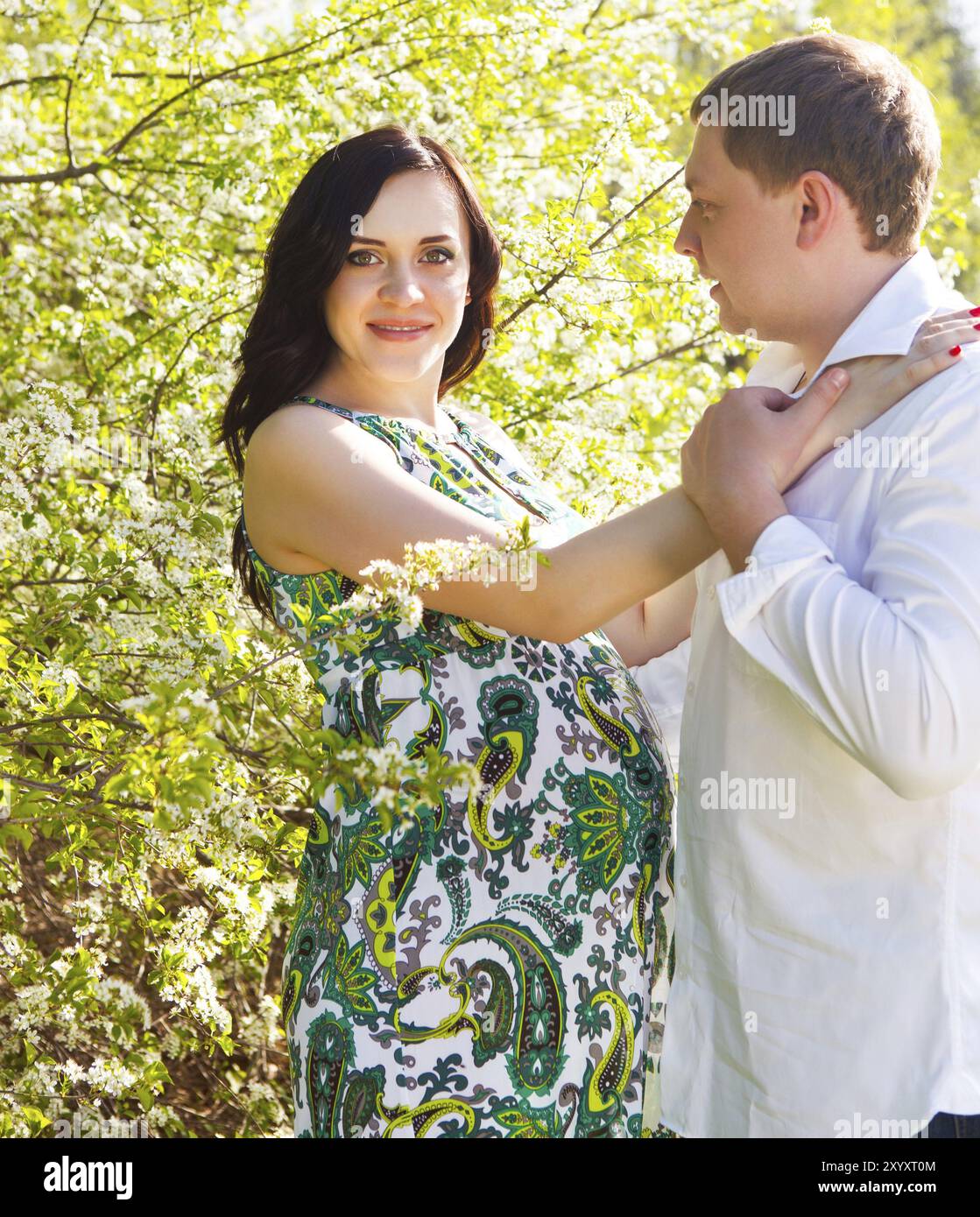 Young happy pregnant couple in the flowering spring park. Outdoors ...