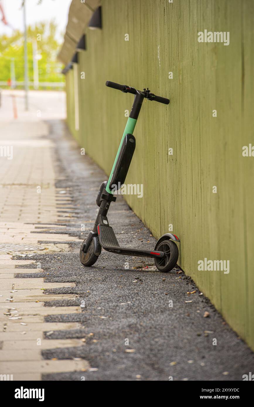 Electric kickbike leaning against a green wall Stock Photo - Alamy