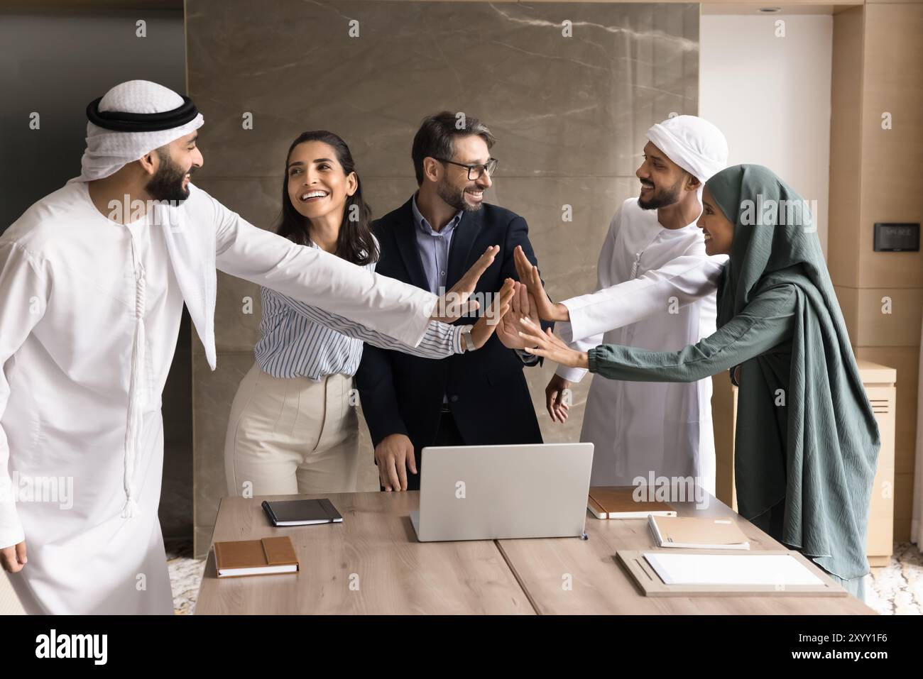 Happy Arabic and European business colleagues giving group high five ...