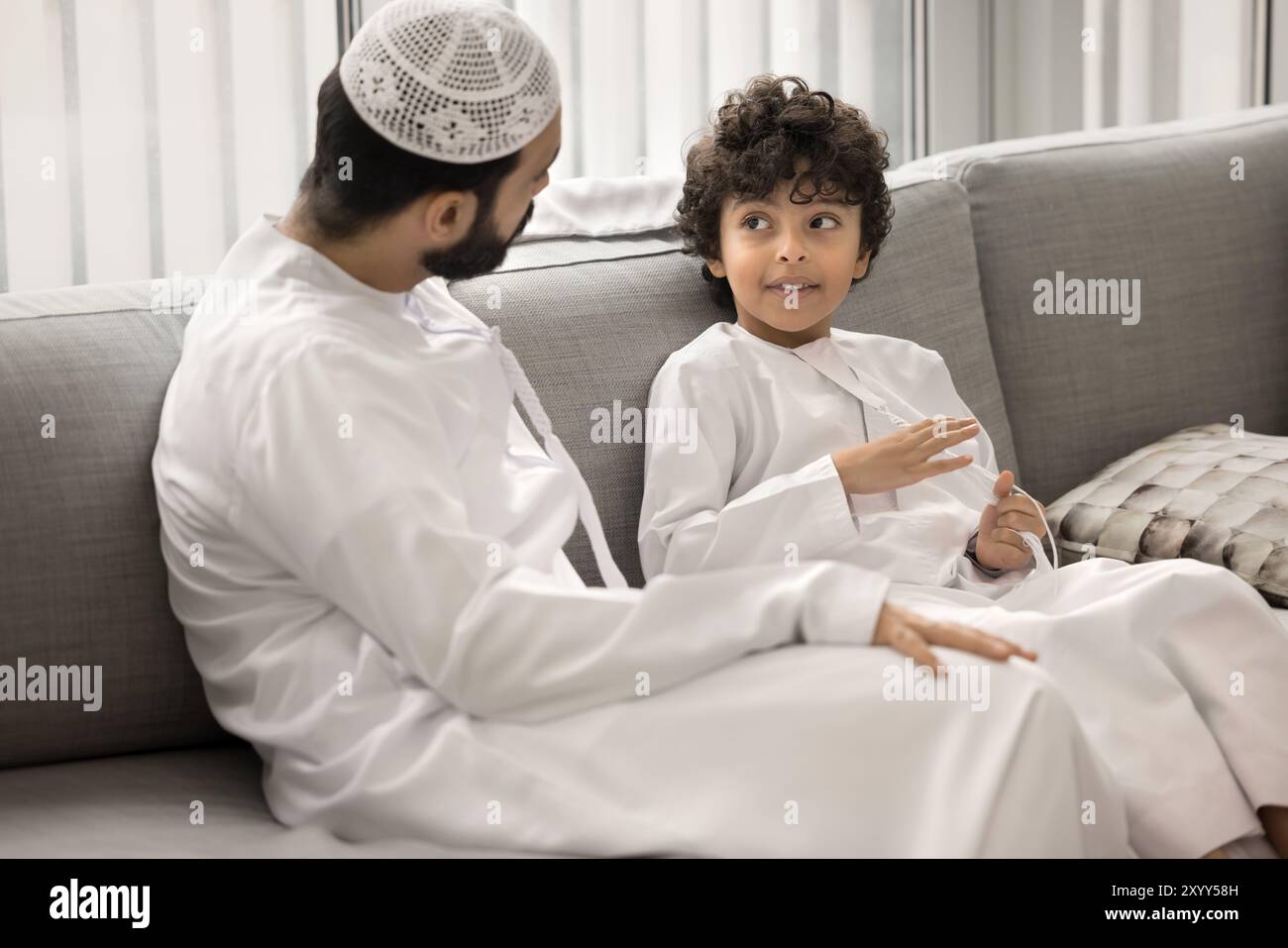 Cute Arabic little boy and loving father sitting on sofa Stock Photo ...