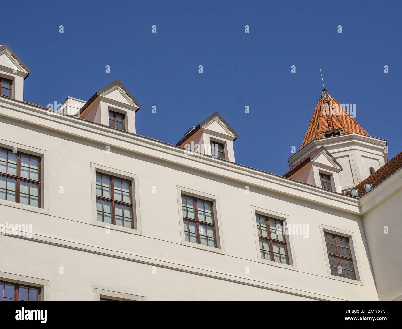 Close-up of a white historic building with orange roofs and a tower ...