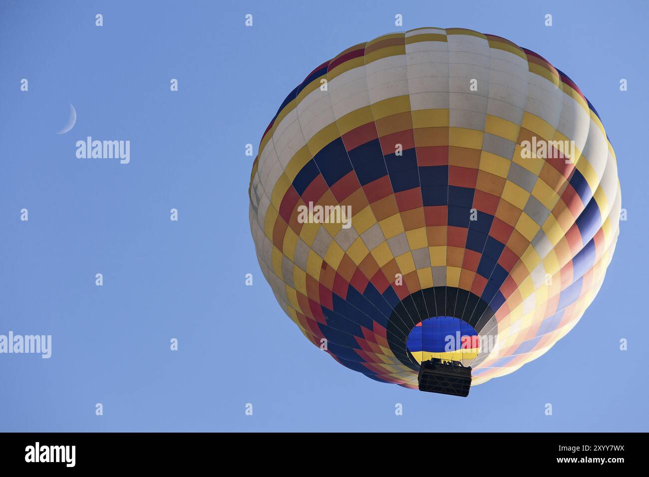 Colorful hot-air balloon in flight and moon seen from below against a ...