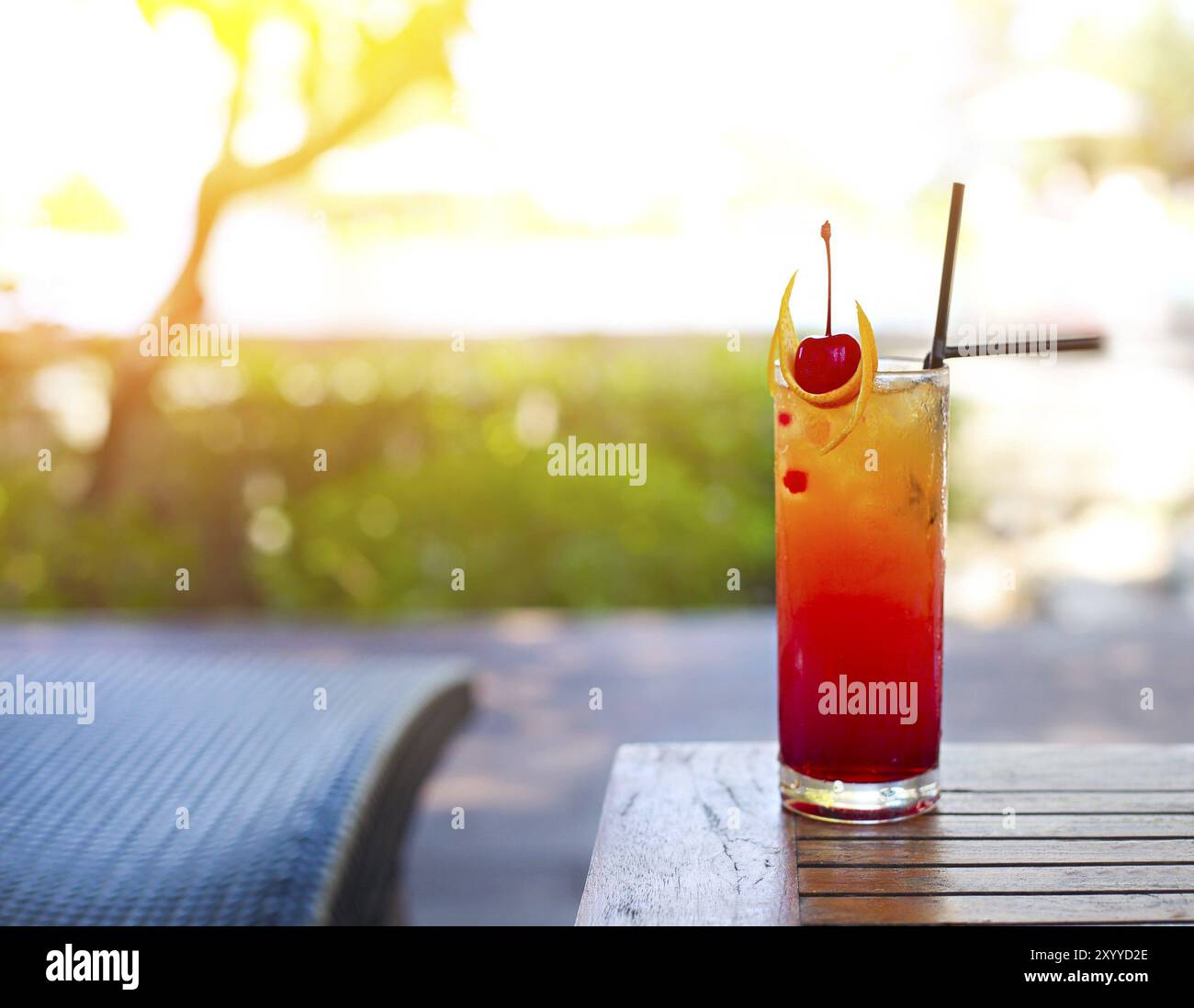 Glass with a bright tequila sunrise cocktail by the pool. Luxury resort ...