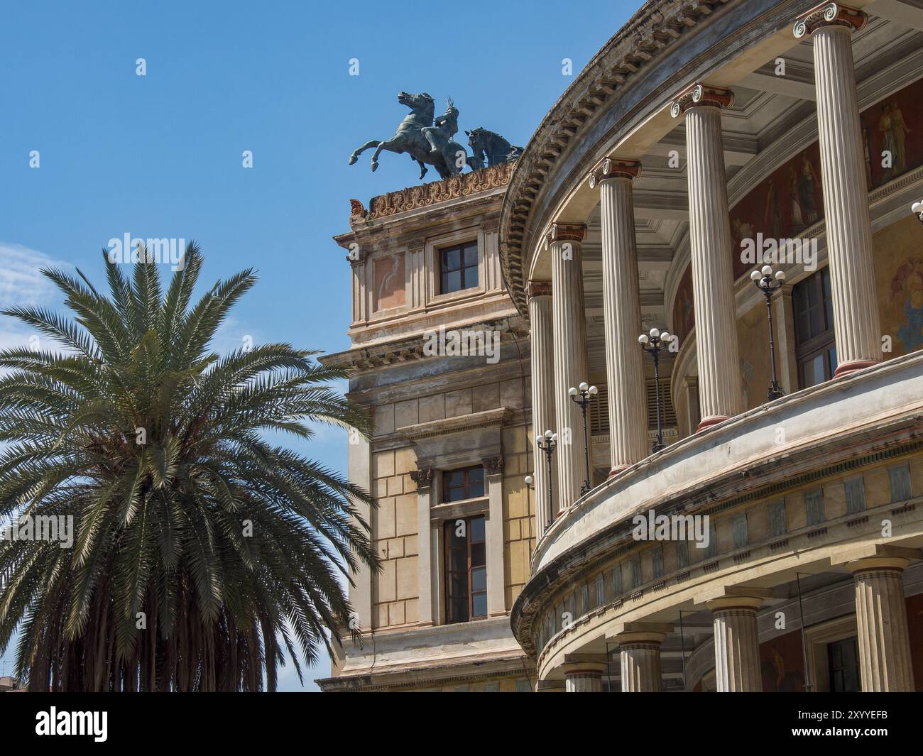 Side of a historic building with columns and bronze statues on the roof ...