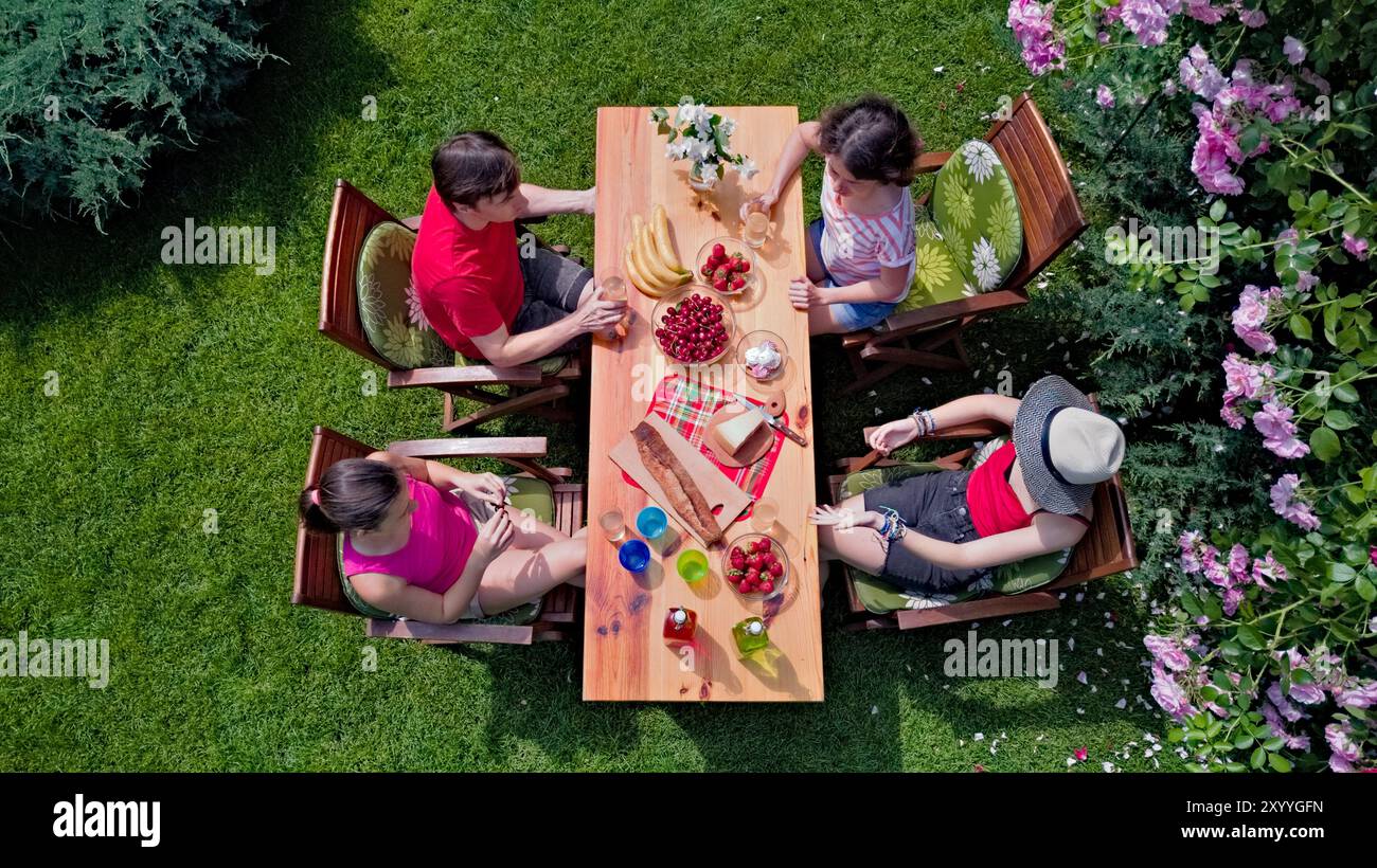 Family and friends eating together outdoors on summer garden party ...