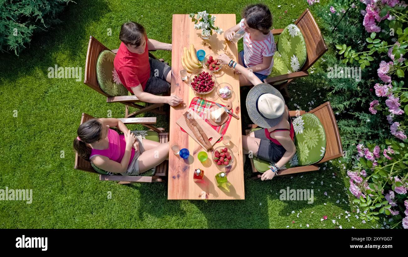 Family and friends eating together outdoors on summer garden party ...