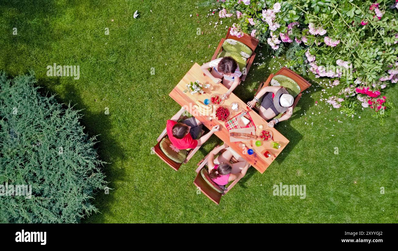 Family and friends eating together outdoors on summer garden party ...