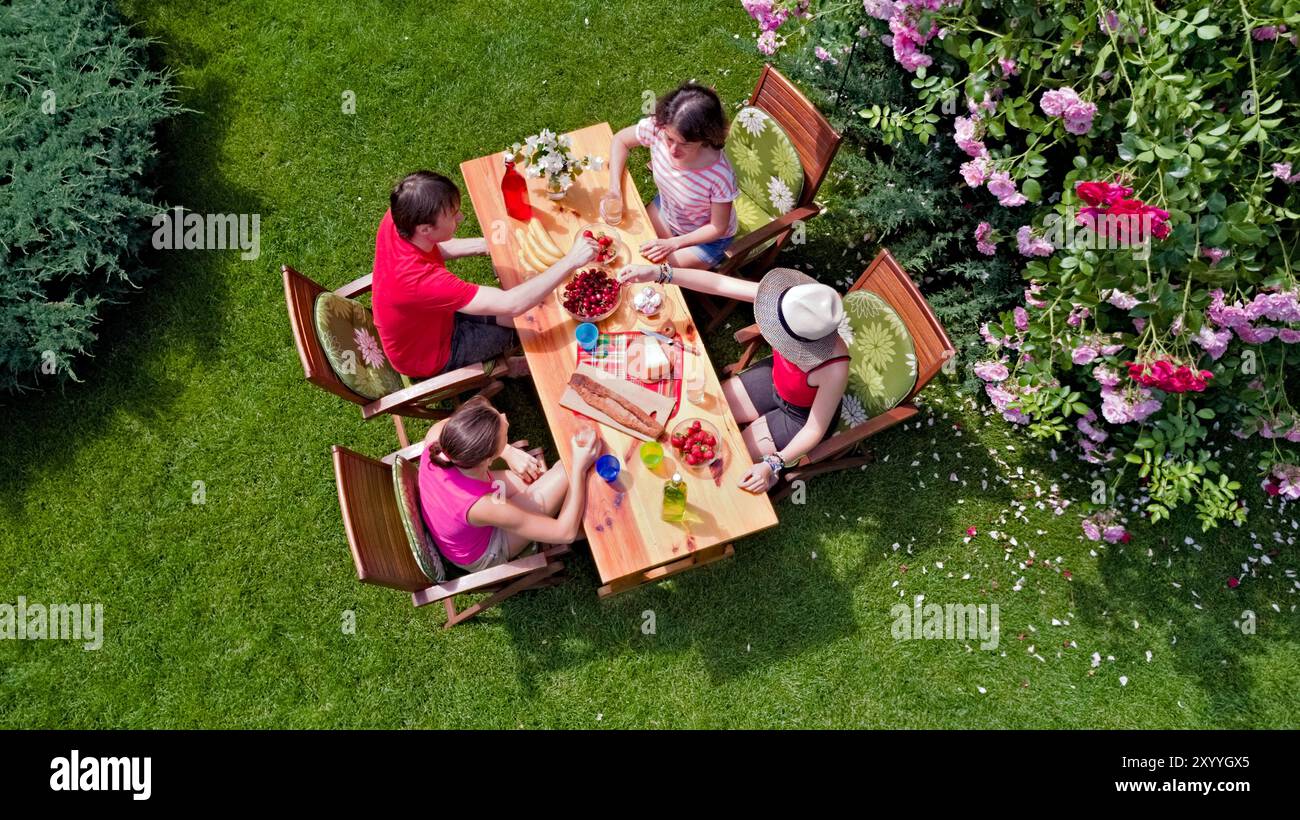 Family and friends eating together outdoors on summer garden party ...
