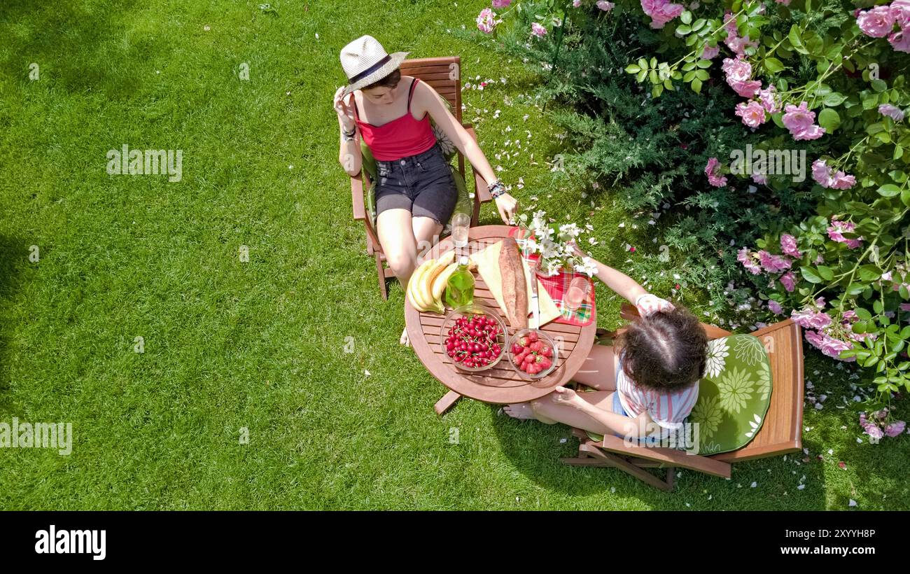 Friends eating together outdoors in summer garden, girls have picnic in ...