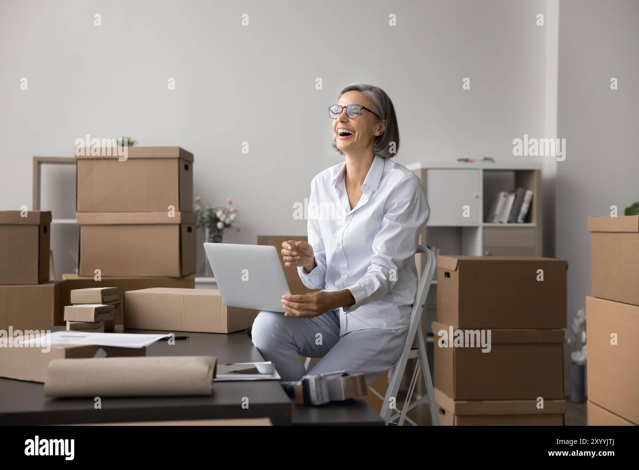 Woman sitting on step ladder with laptop in warehouse room Stock Photo ...