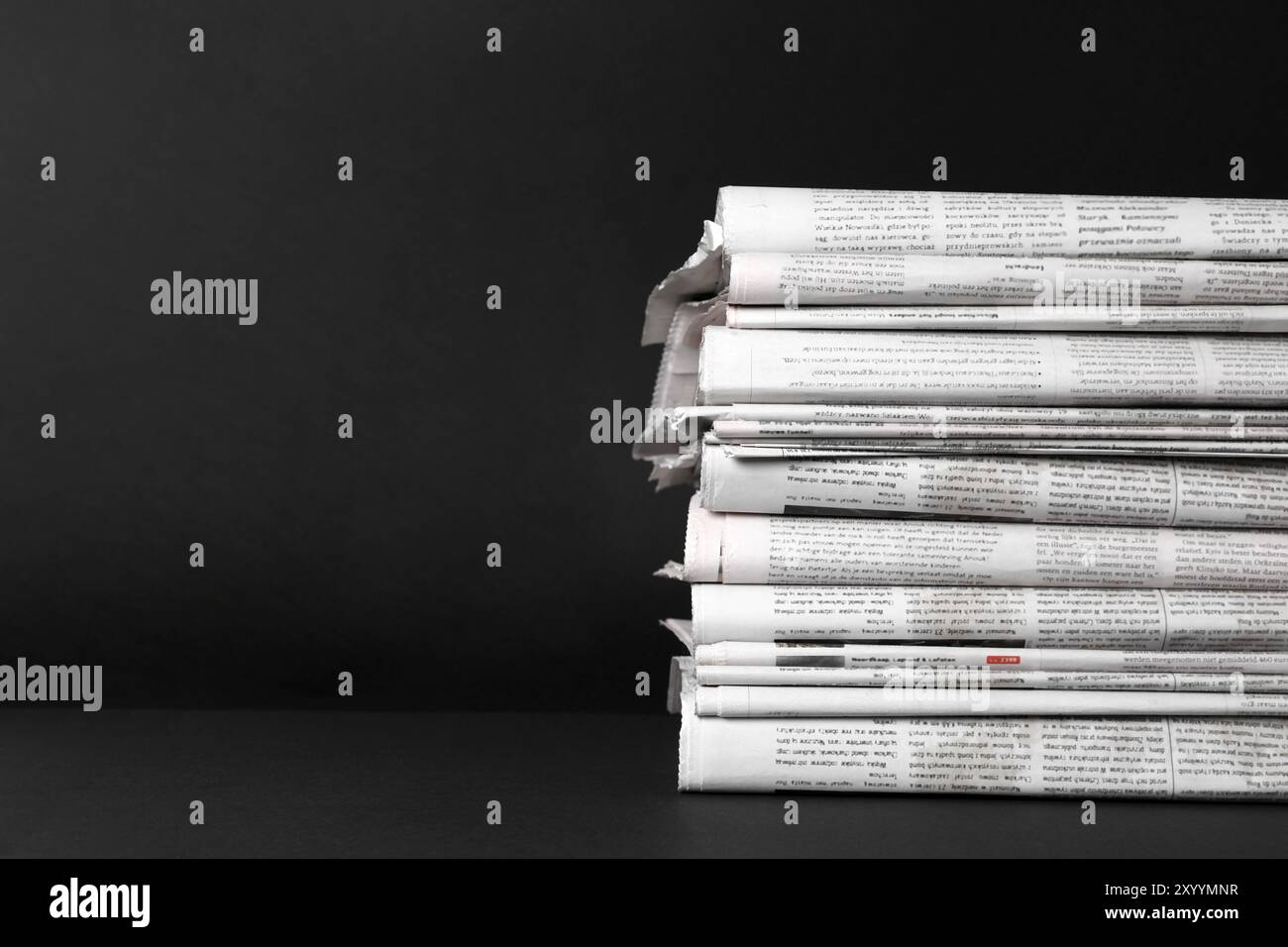 Stack of newspapers in different languages on black background. Space ...