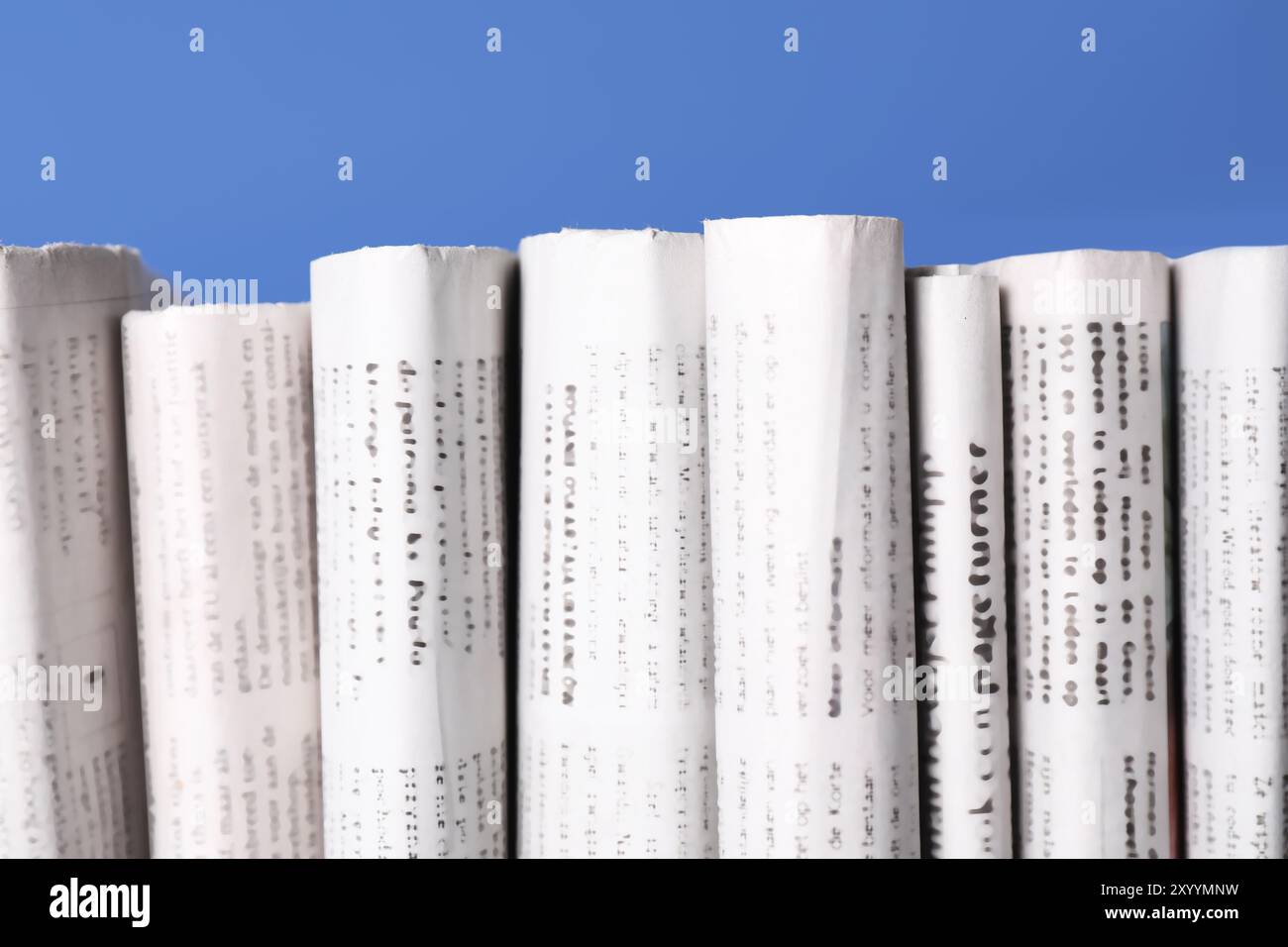 Many newspapers in different languages on blue background, closeup ...