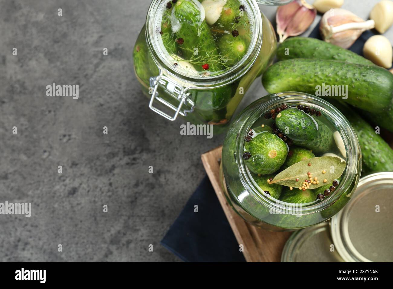 Making pickles. Fresh cucumbers and spices in jars on grey table, flat ...