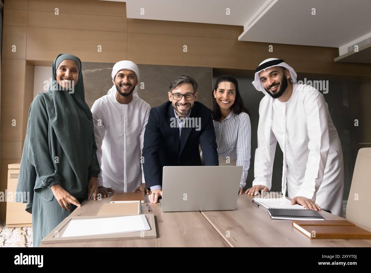 Diverse Caucasian and Middle Eastern business team posing at laptop ...