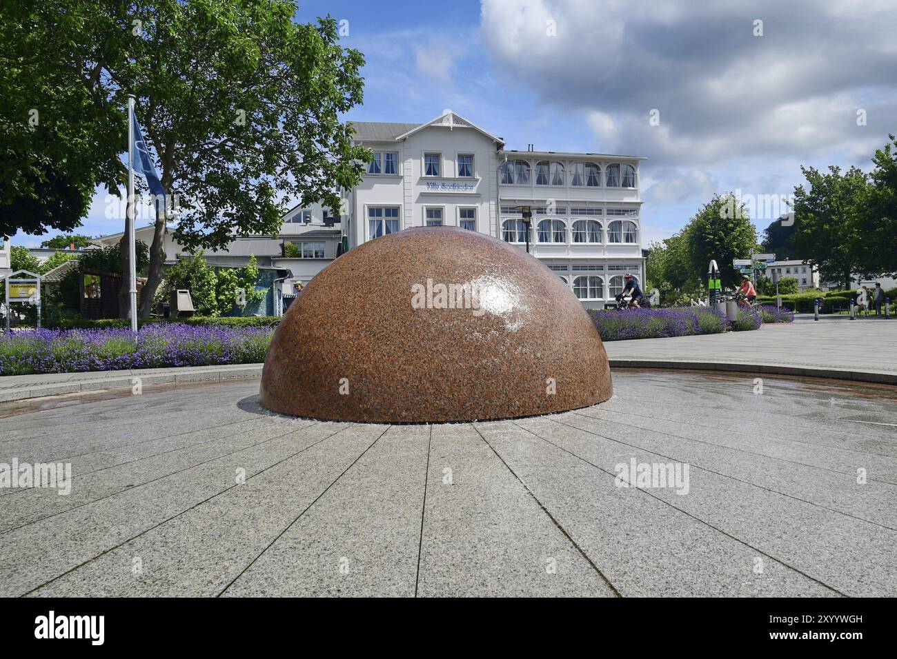 Modern round fountain on a paved square with a view of a building ...