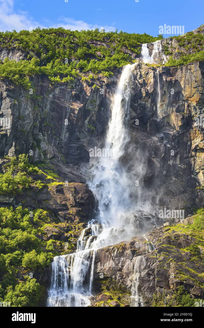 Waterfall, mountain cliff and green trees on the way to Briksdal or ...