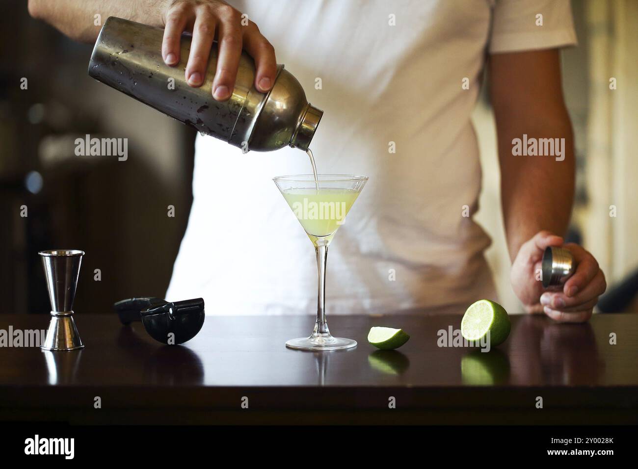 Barman at work, preparing cocktails. Pouring martini to cocktail glass ...