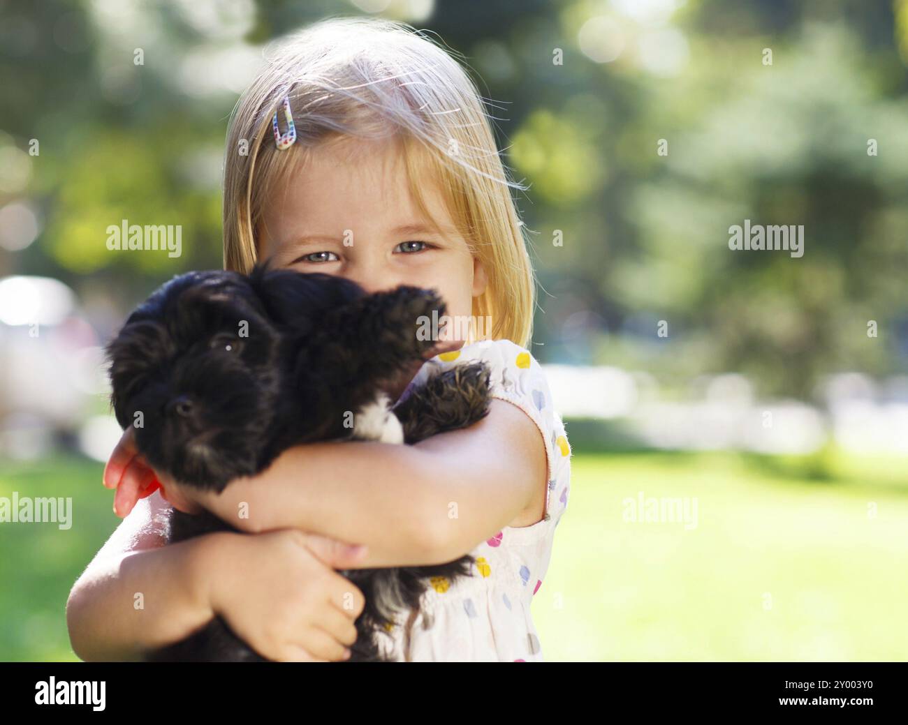 Cute little girl hugging dog puppy outdoors. Friendship and care ...