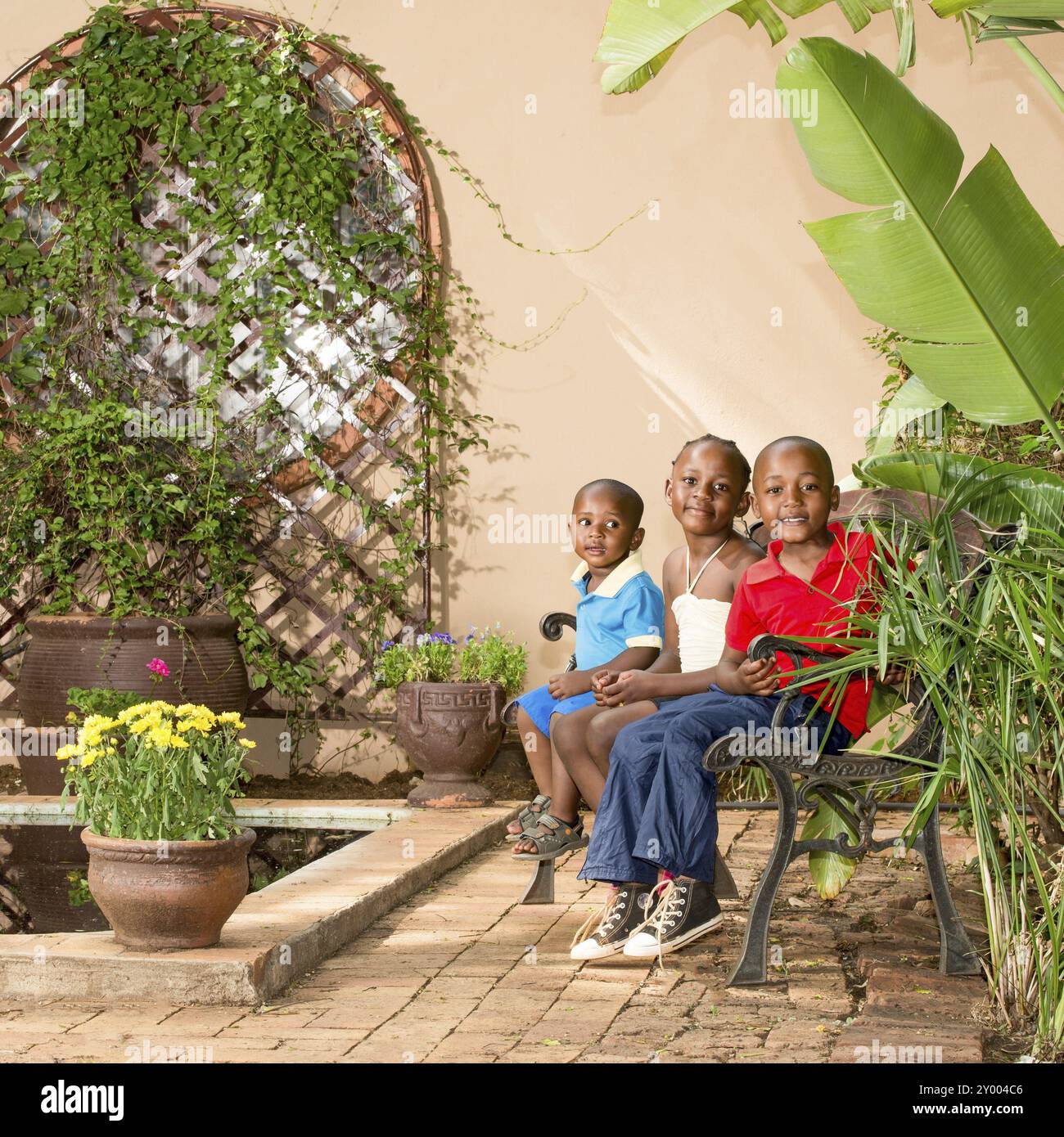 Two brothers and one sister sitting together on a bench by a small pond ...