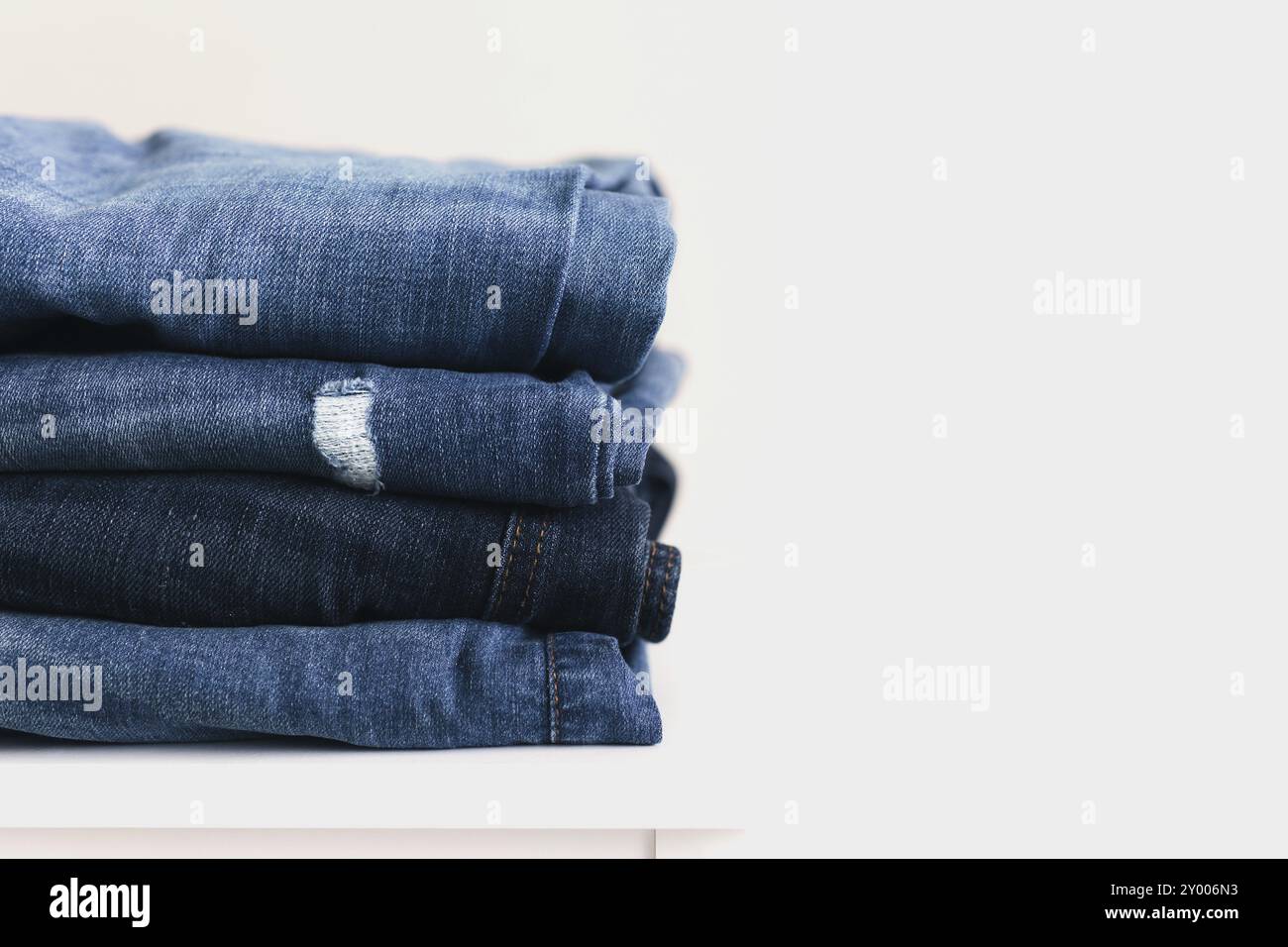A stack of blue denim jeans or pants. Textile industry concept ...