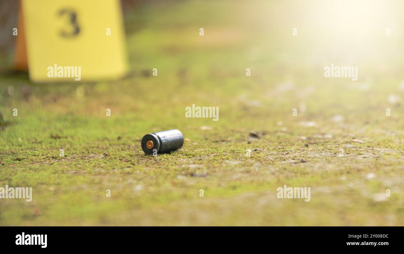 Spent bullet casing lying on the ground with blur number 3 sign ...