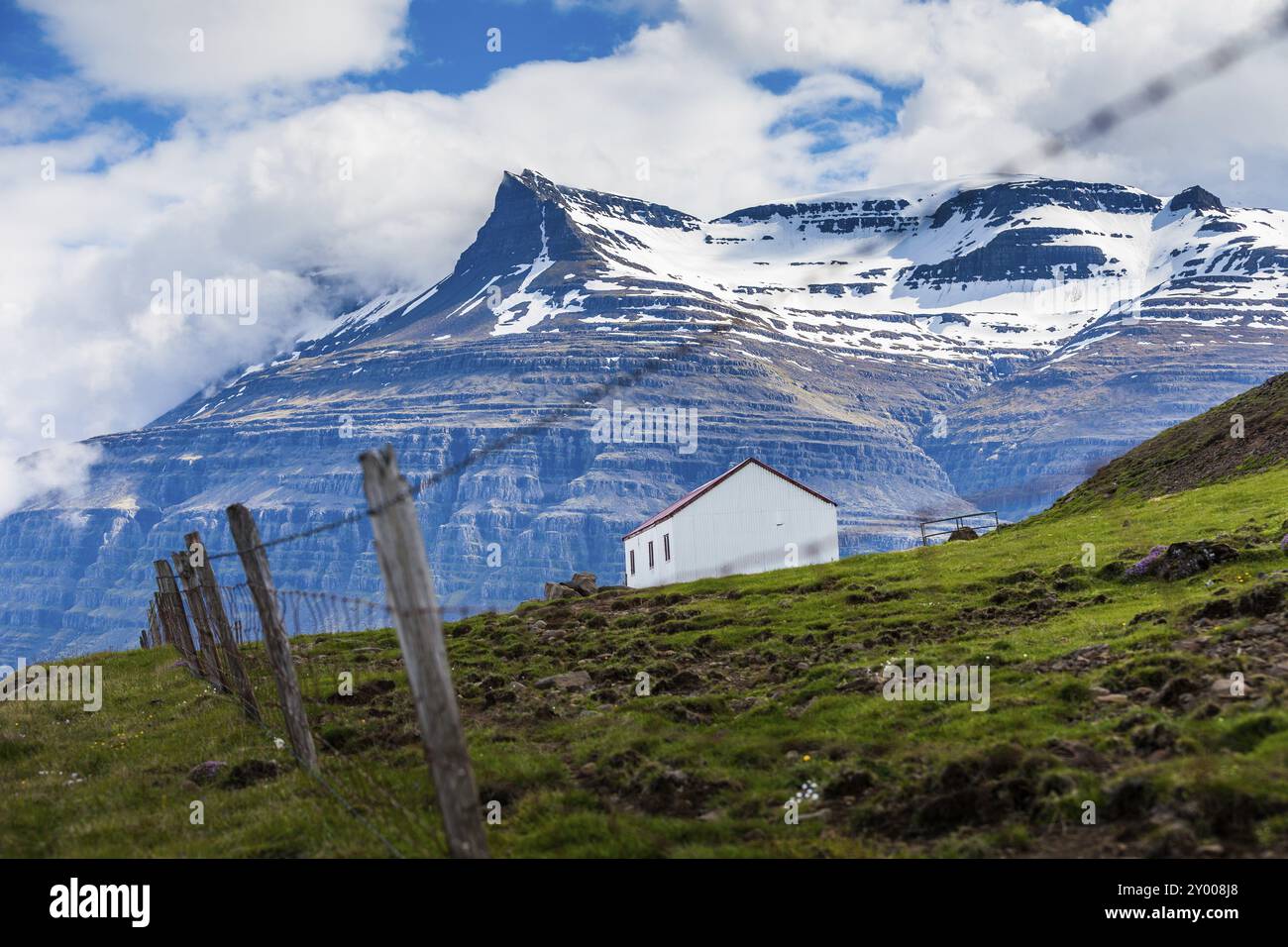 White shed with a red roof in front of snow covered mountains on ...