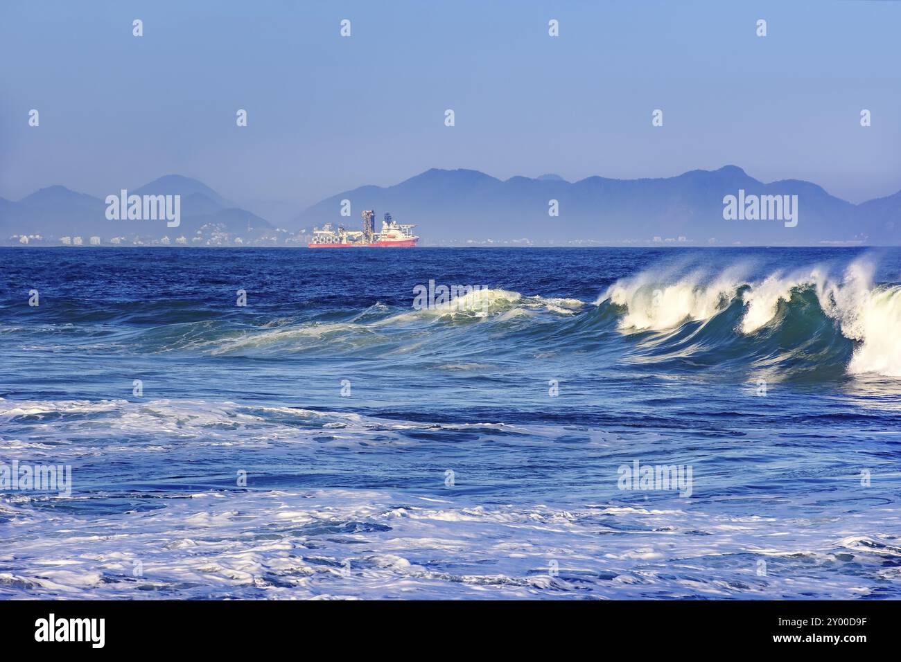Wave breaking on the Devil's beach in Rio de Janeiro with cargo ship ...
