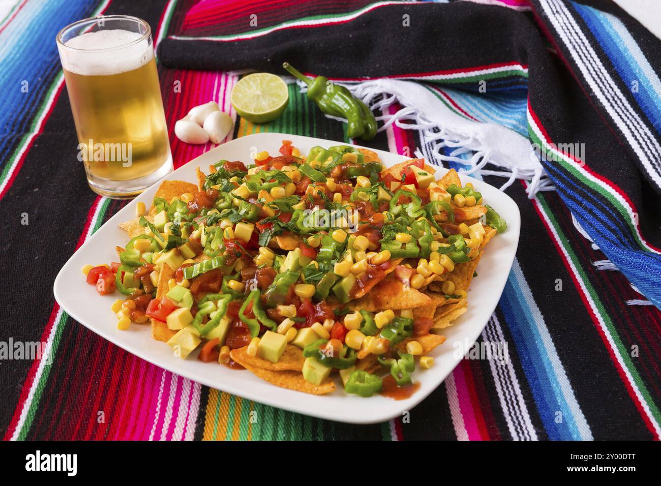 Nachos salad and beer in a square plate over a colored poncho Stock ...