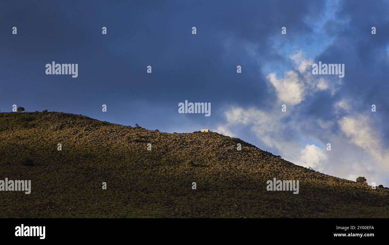 Sunlight and shadow play across a grassy hill under a dramatic sky with ...