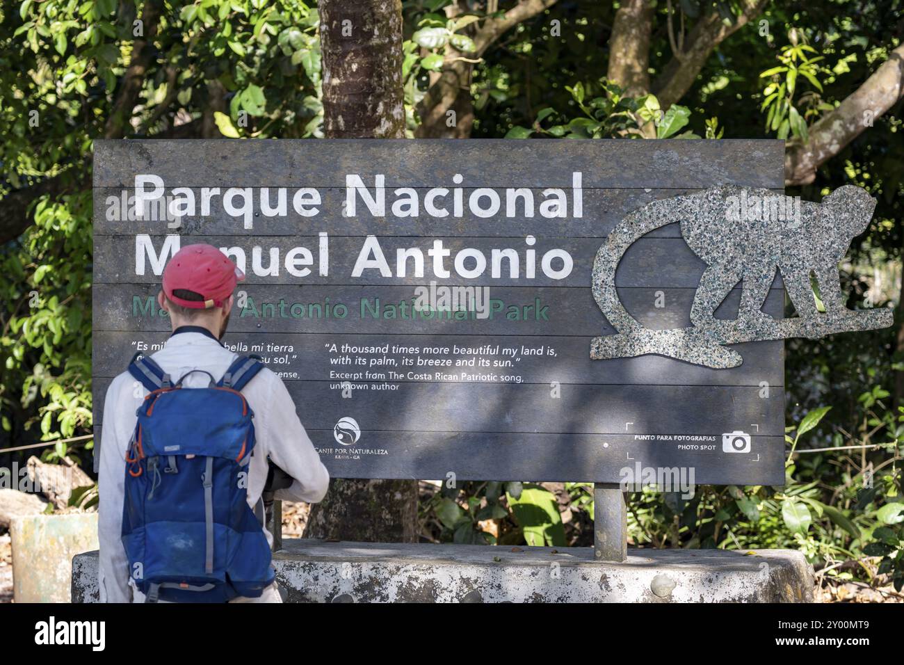 Tourist standing in front of sign at the entrance of the national park ...