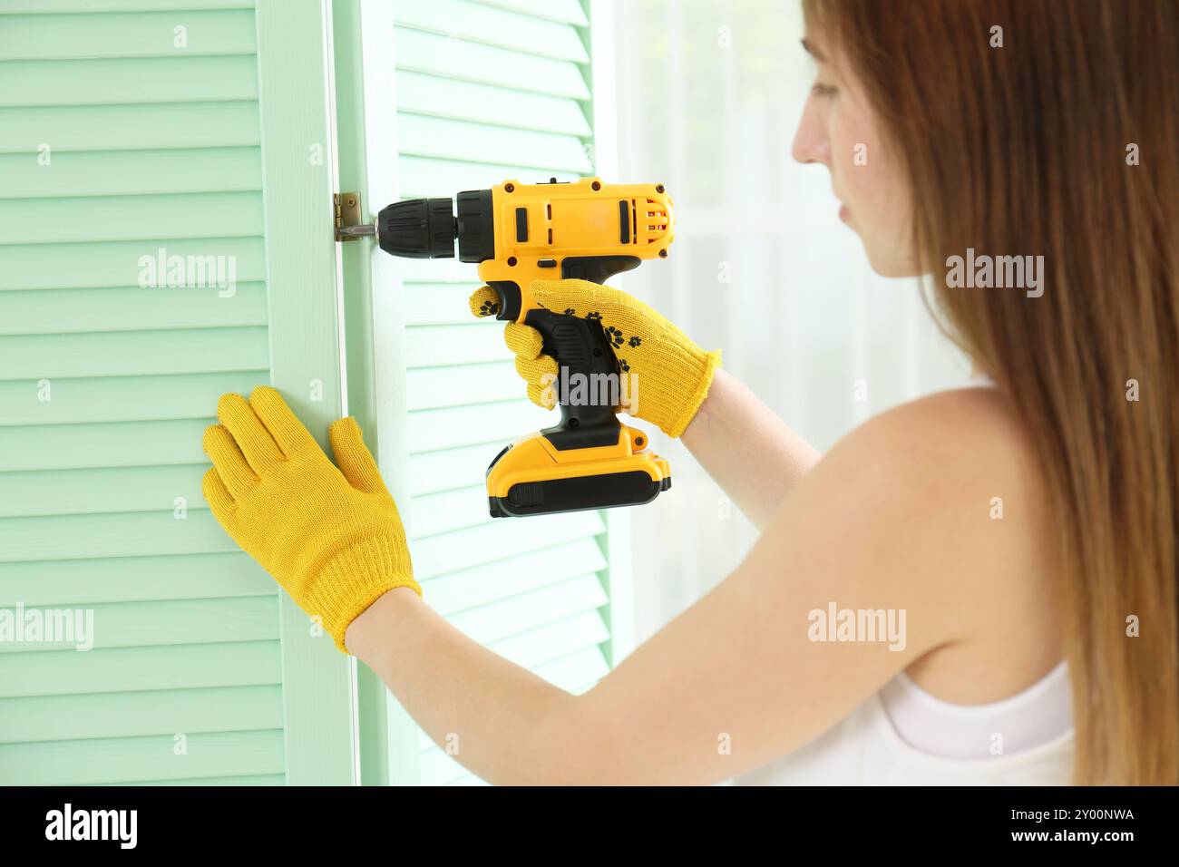 Woman with electric screwdriver assembling folding screen indoors Stock ...