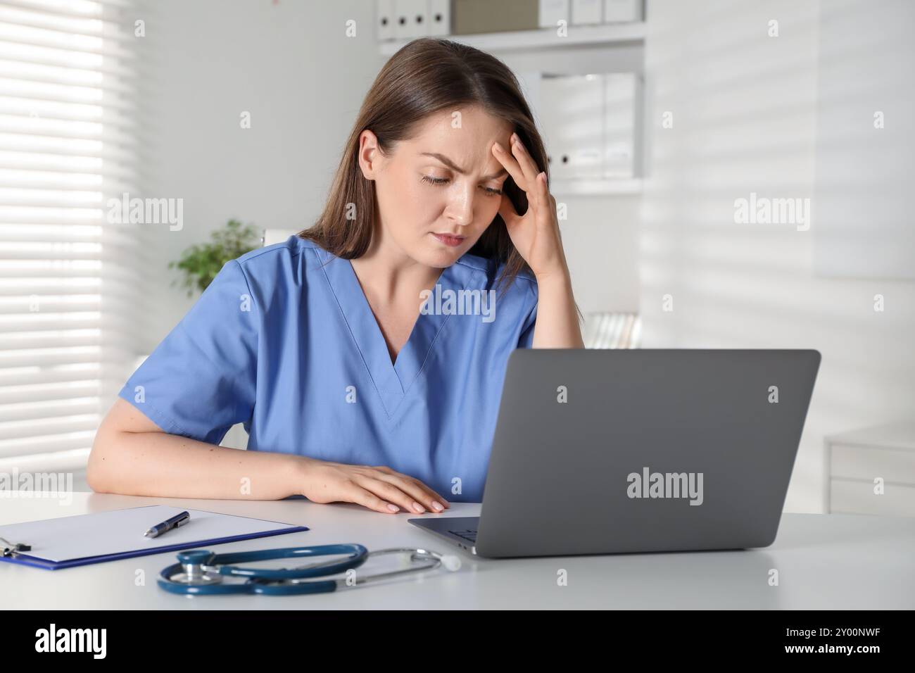 Tired nurse working at desk in hospital Stock Photo - Alamy
