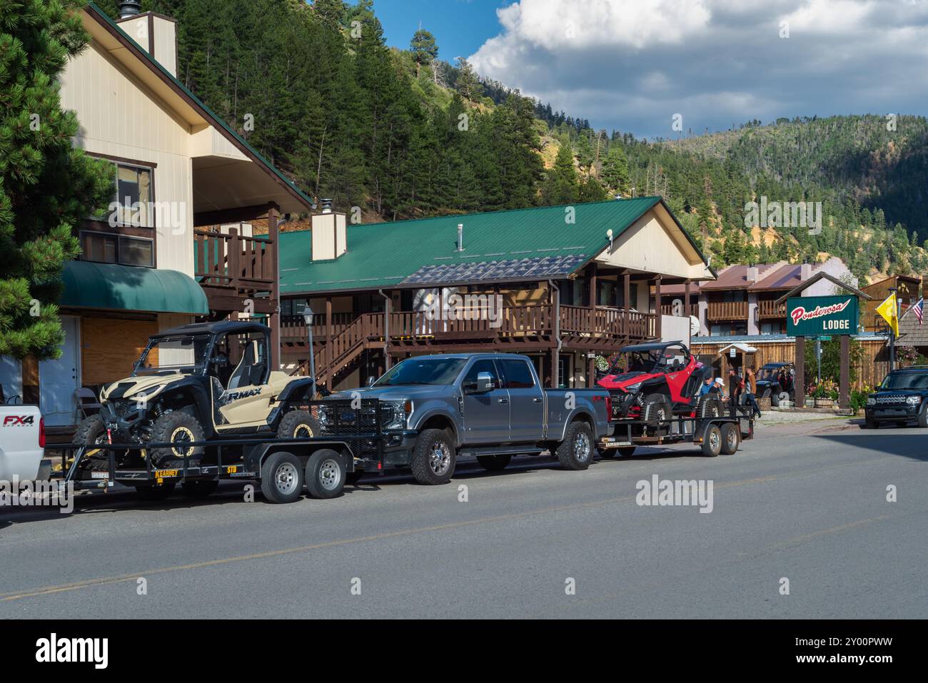 Side by sides on trailers behind pickups parallel parked on Main Street ...