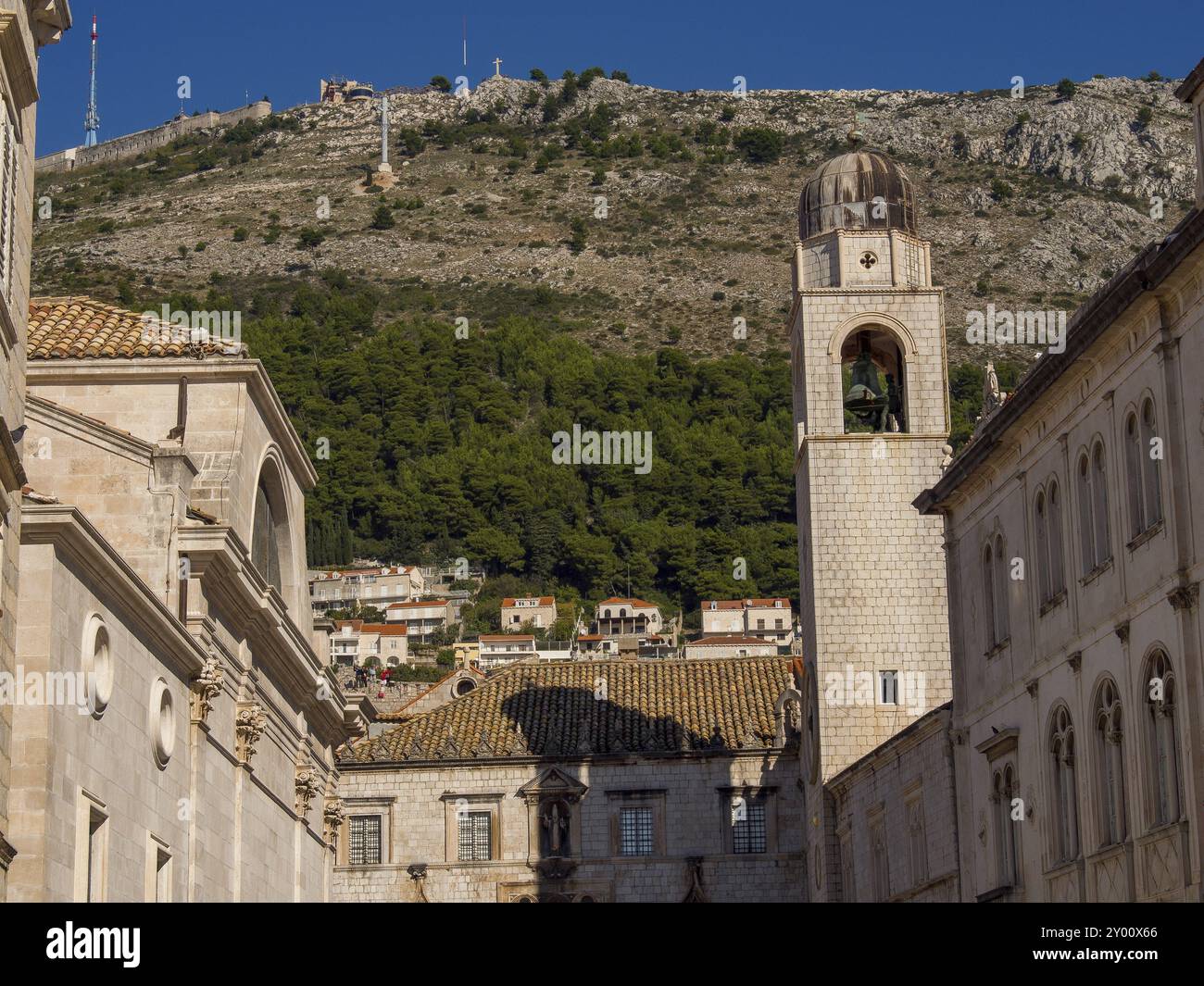 Bell tower and historical buildings in front of a hill covered with ...