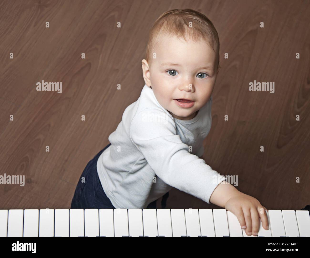 Portrait of little baby child play music on black and white piano ...