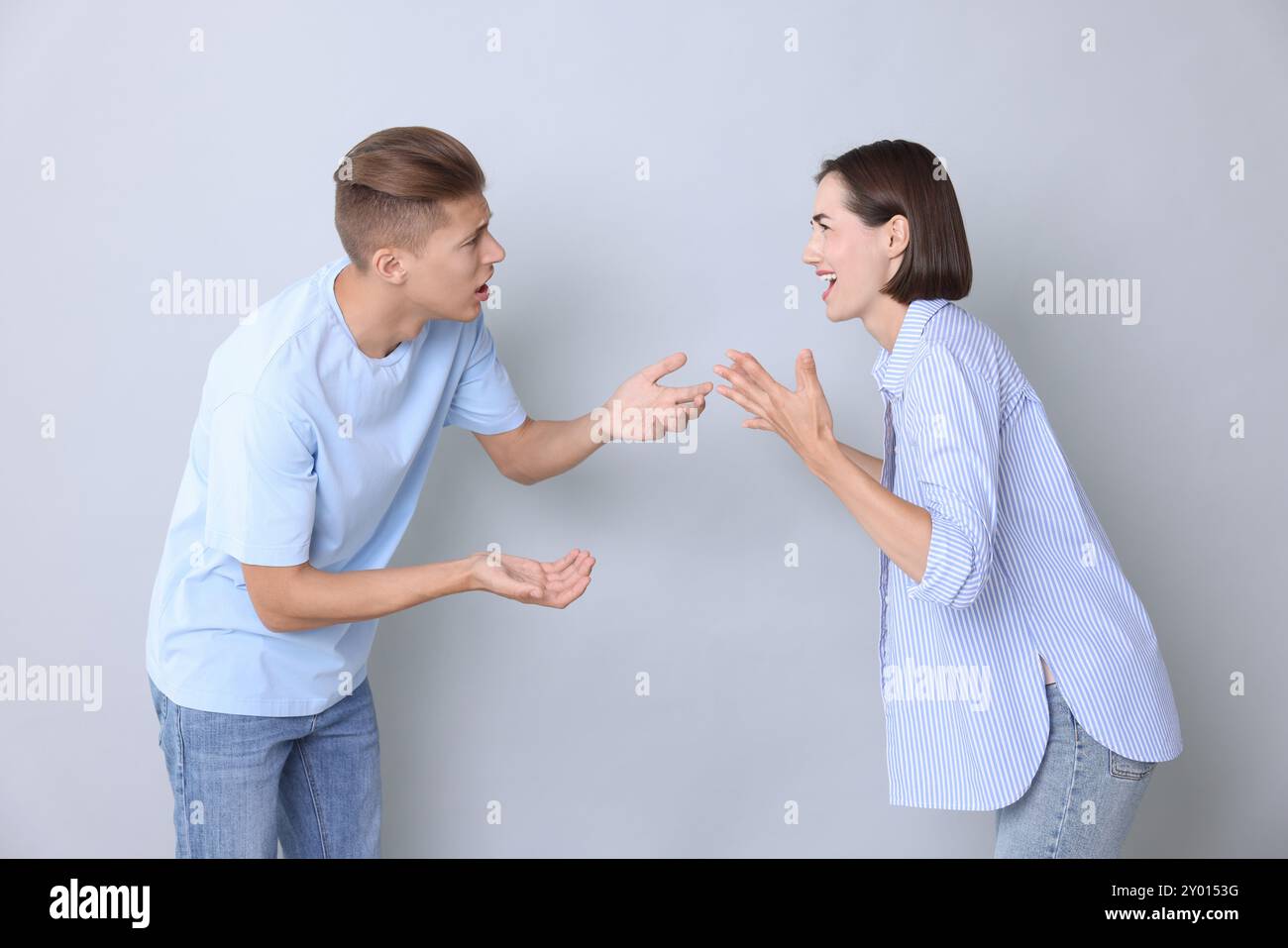 Emotional young couple having quarrel on grey background Stock Photo ...