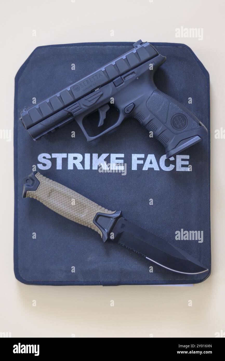 Black pistol and hunting knife with beige handle lie on a protective ...